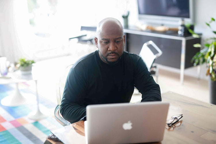 Person focused on computer in their living room – pre&ent